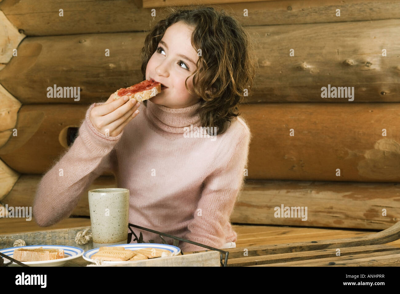 Girl having snack, looking away Stock Photo - Alamy