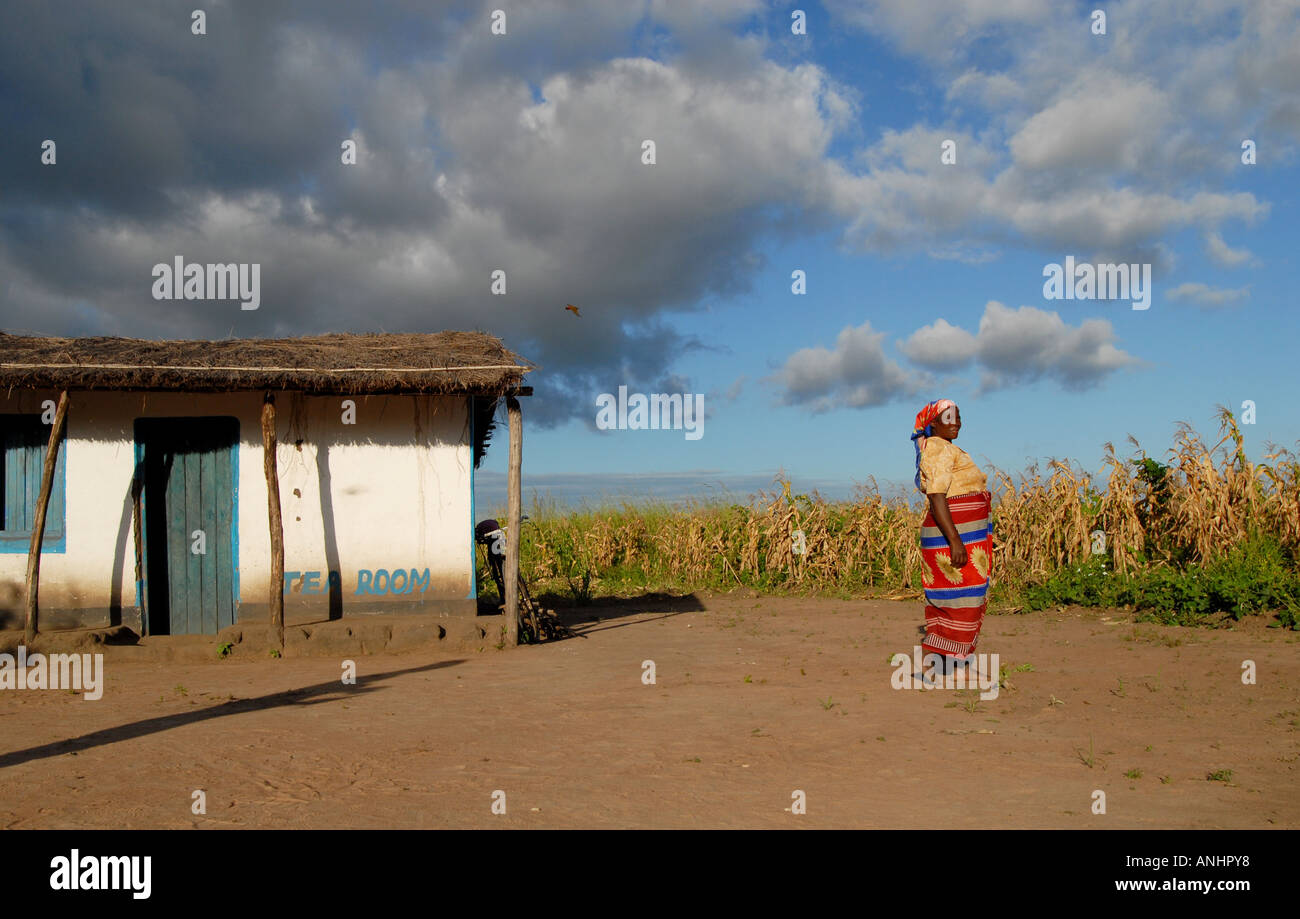 Enelesi Lamusi, a woman farmer, stands next to her new house on her ...