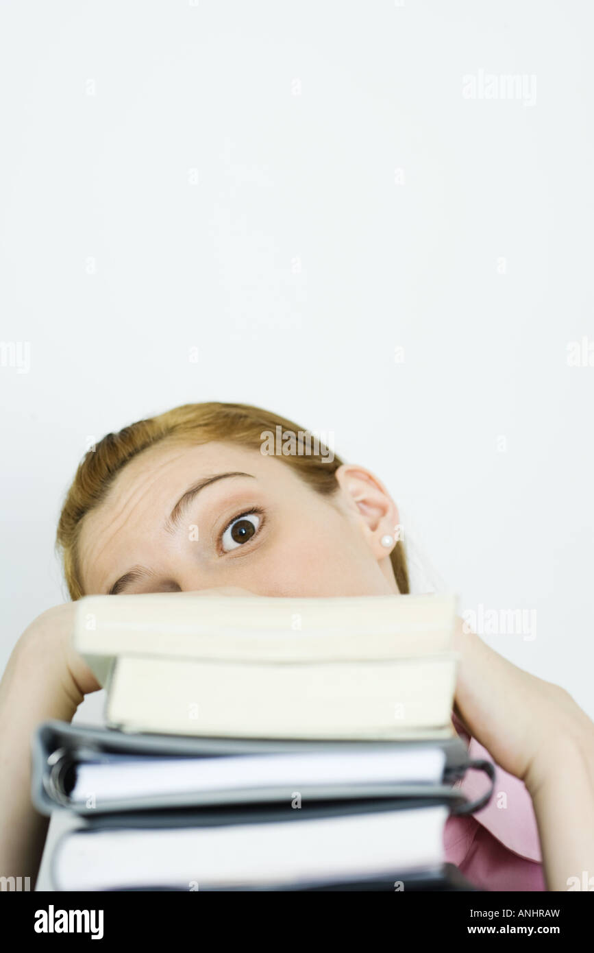Young woman looking at camera over stack of books, head tilted Stock ...