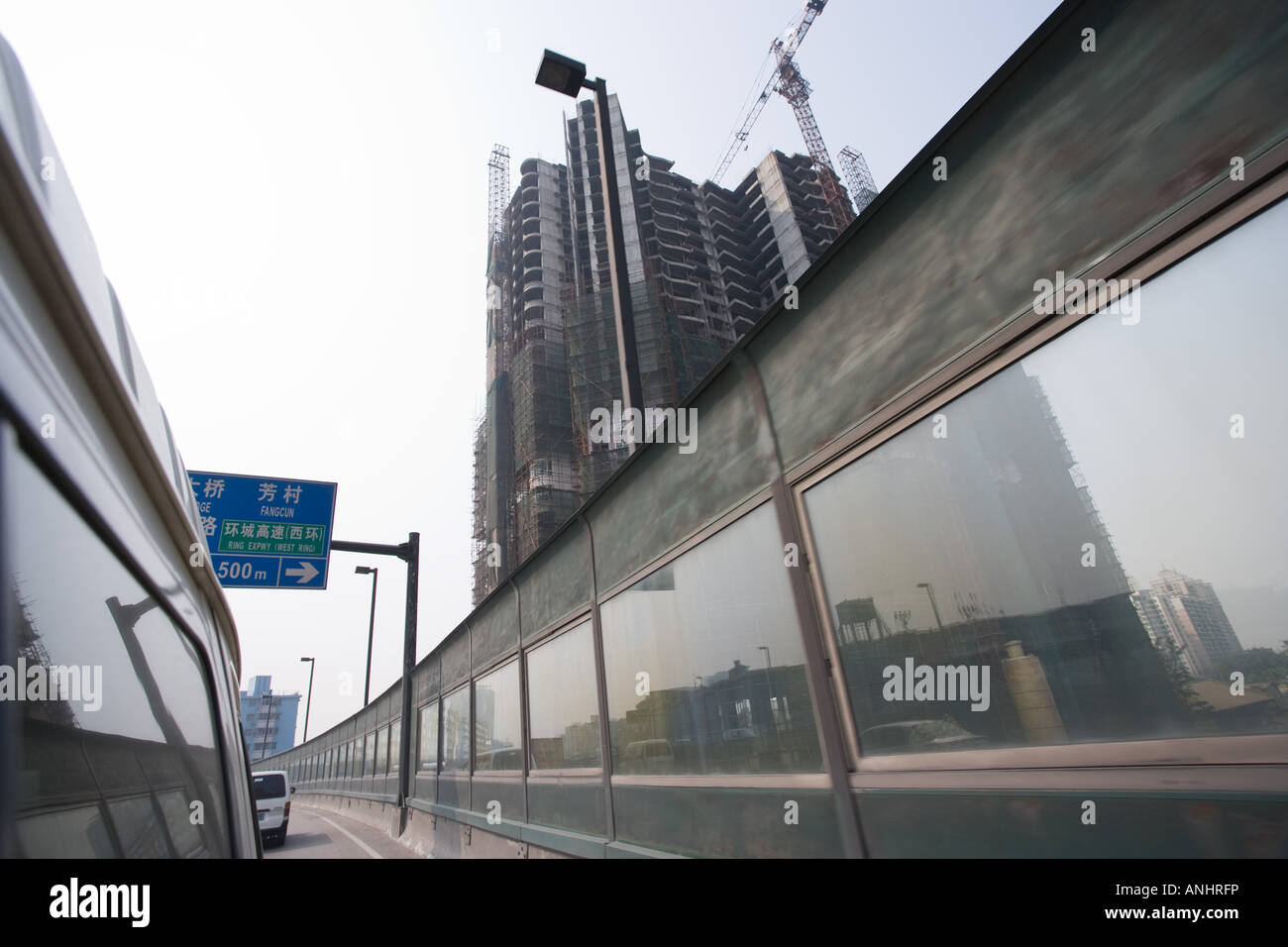 Wall on side of road, viewed from vehicle, high rise under construction ...