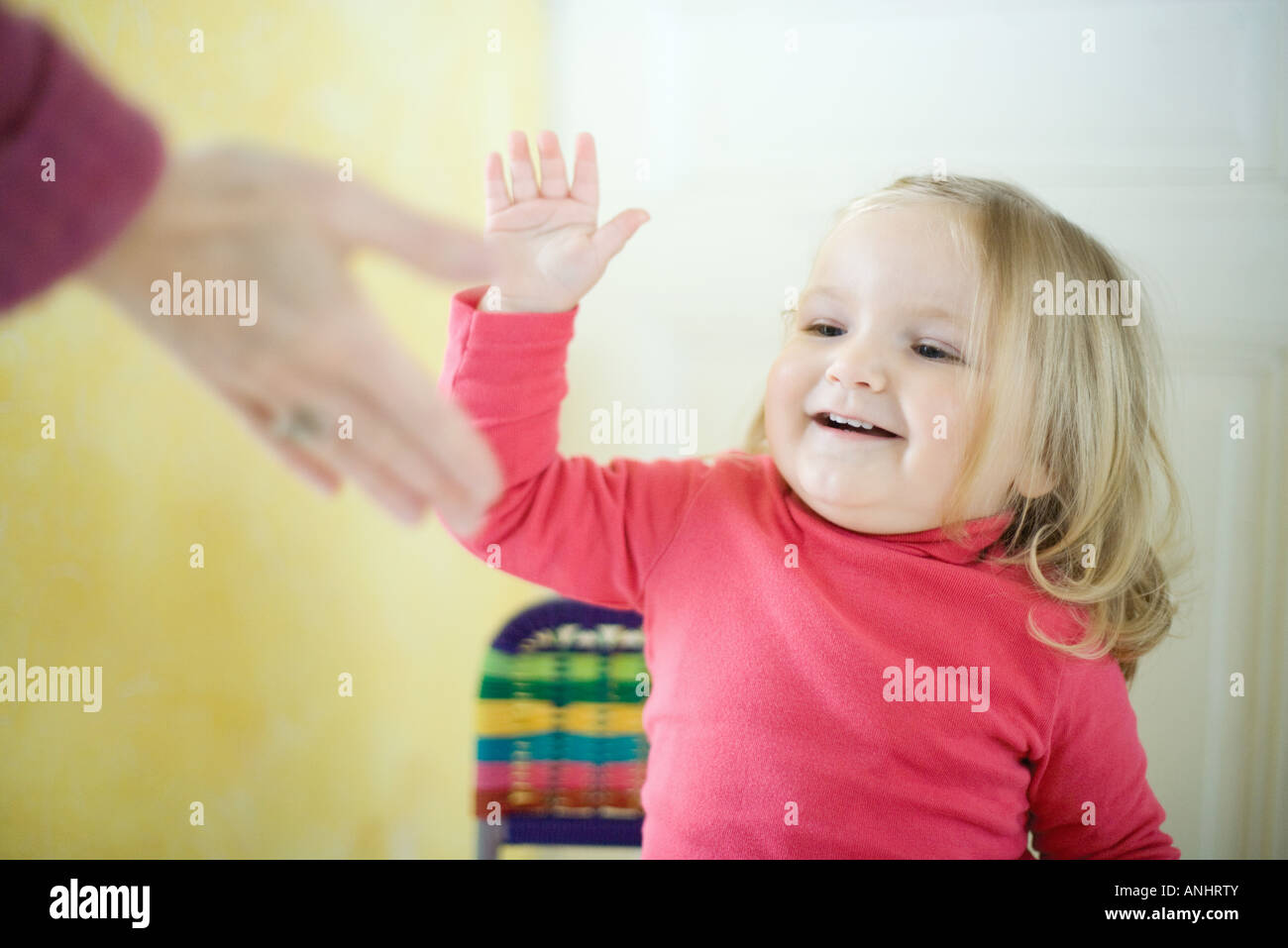 Blonde toddler girl giving adult high five Stock Photo - Alamy