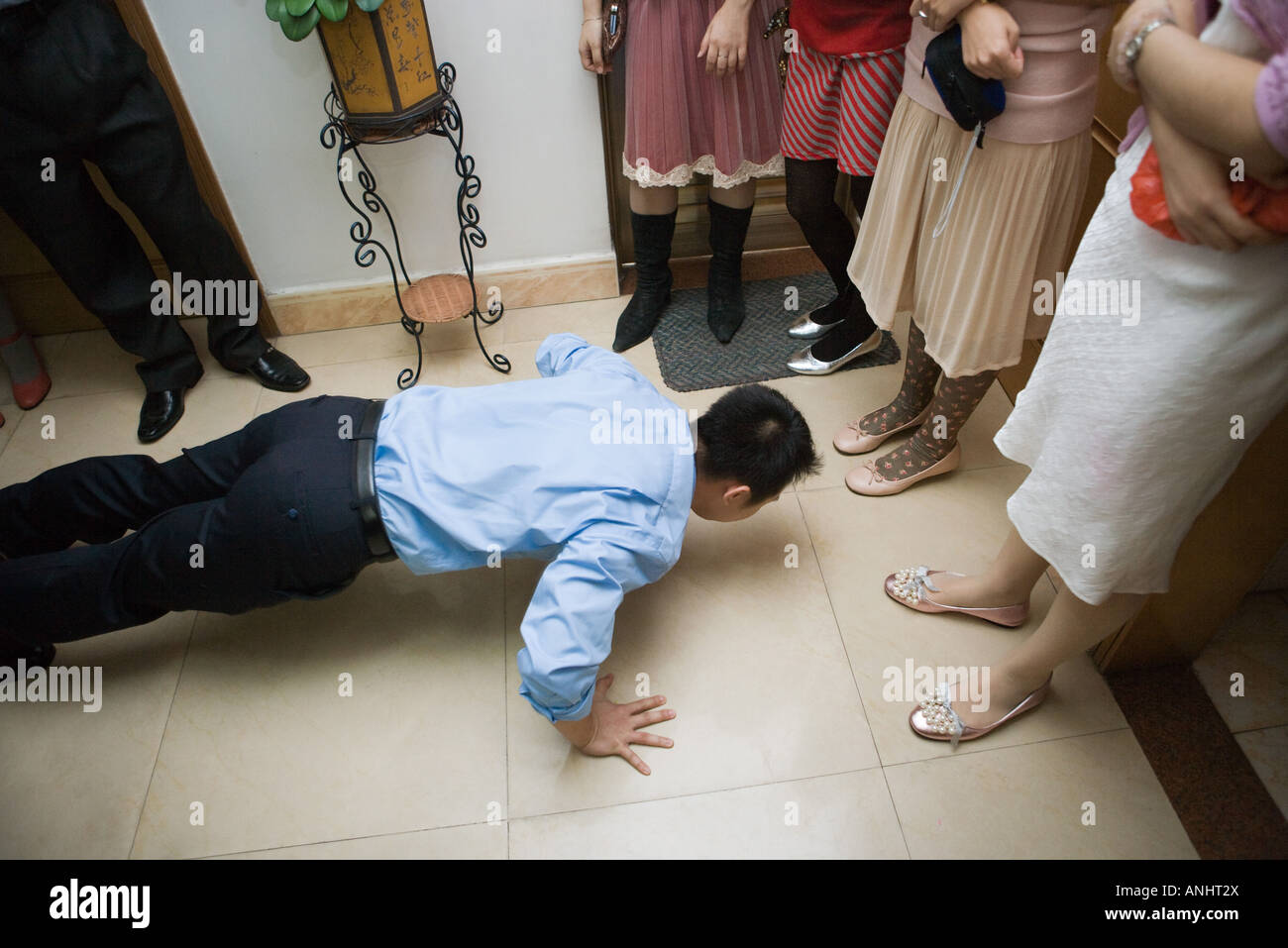 Chinese wedding, groom doing push-ups while women watch Stock Photo - Alamy