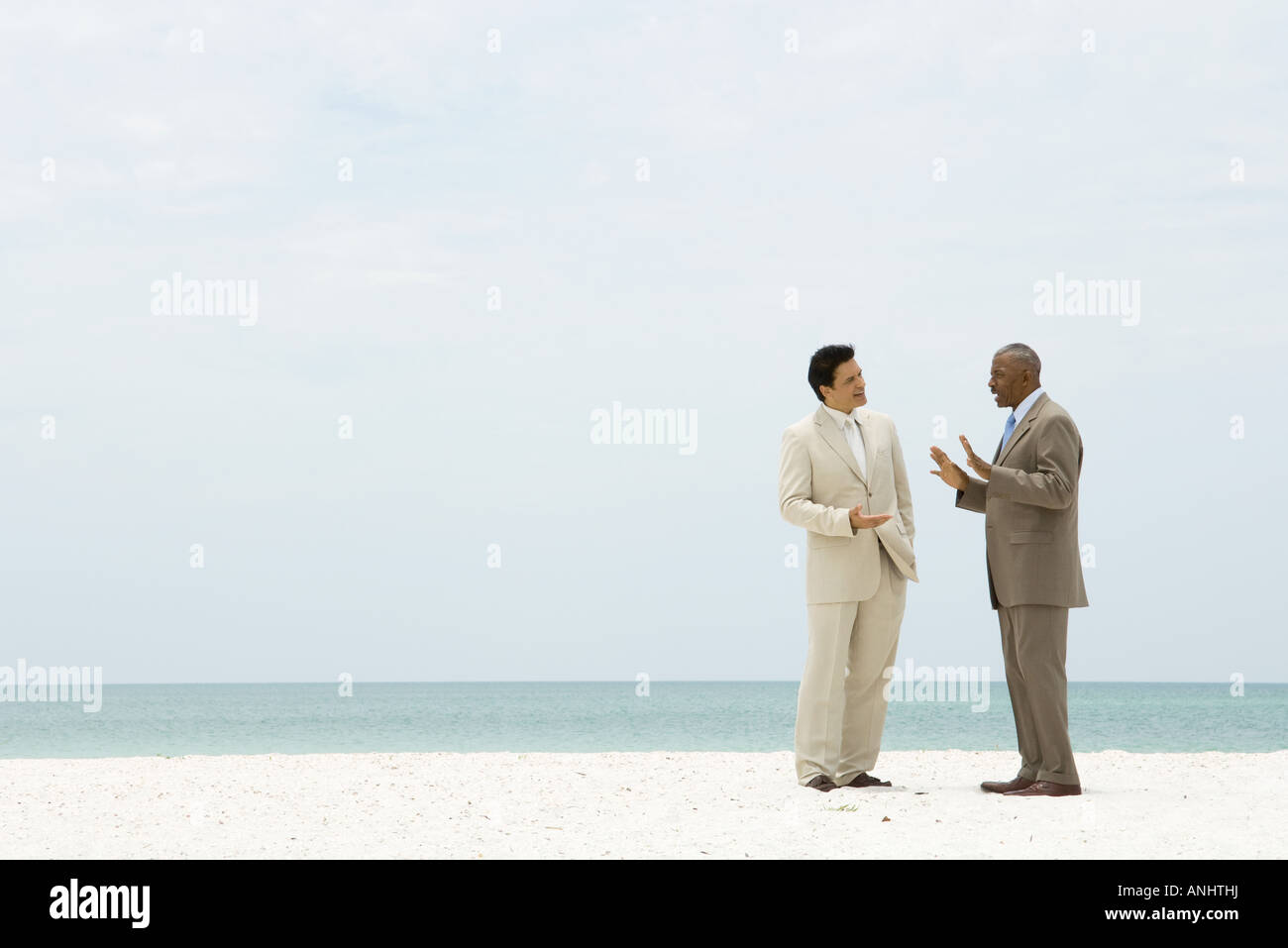 Two businessman standing on beach having conversation Stock Photo - Alamy