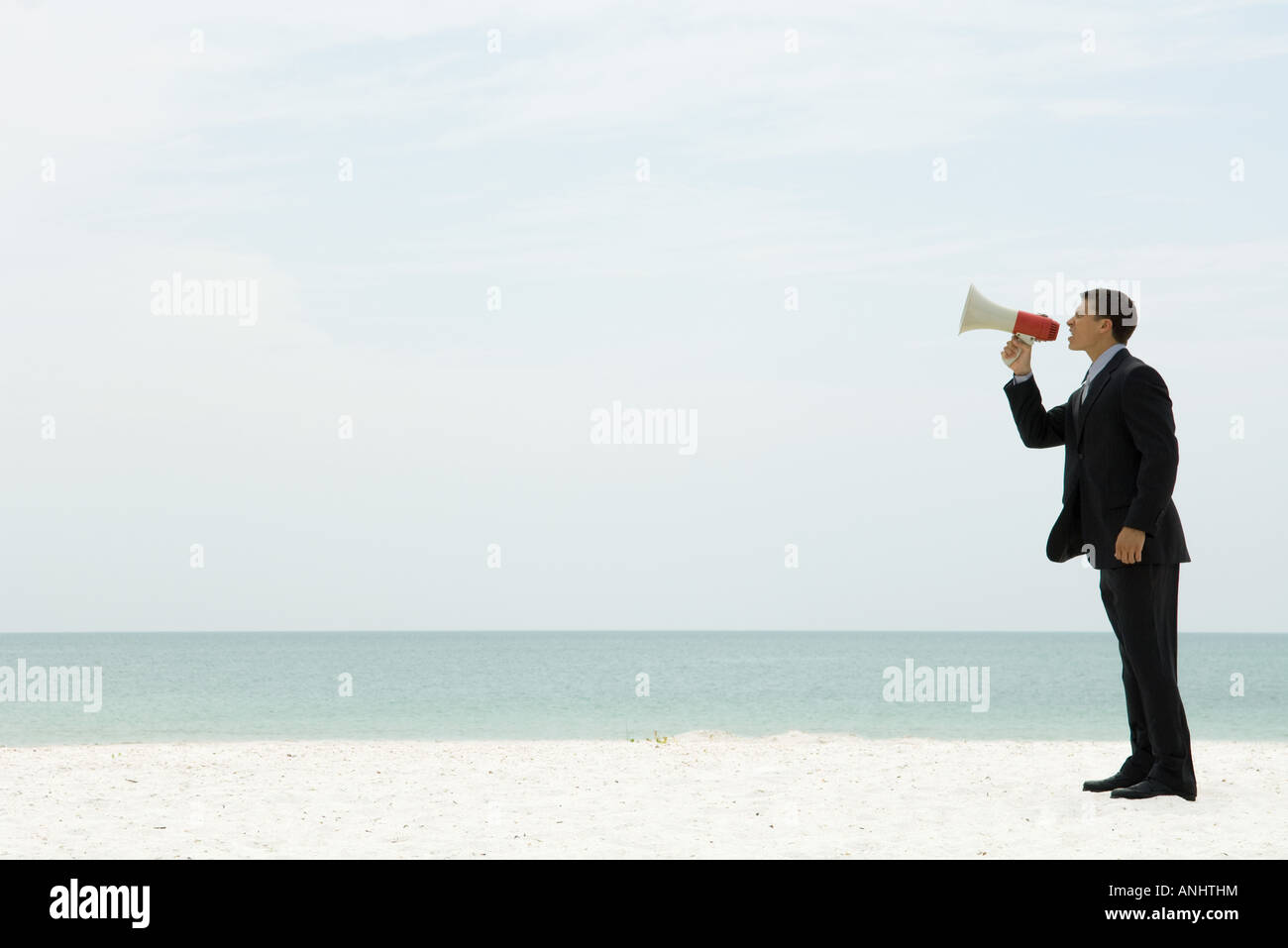 Businessman standing at the beach shouting into megaphone Stock Photo ...