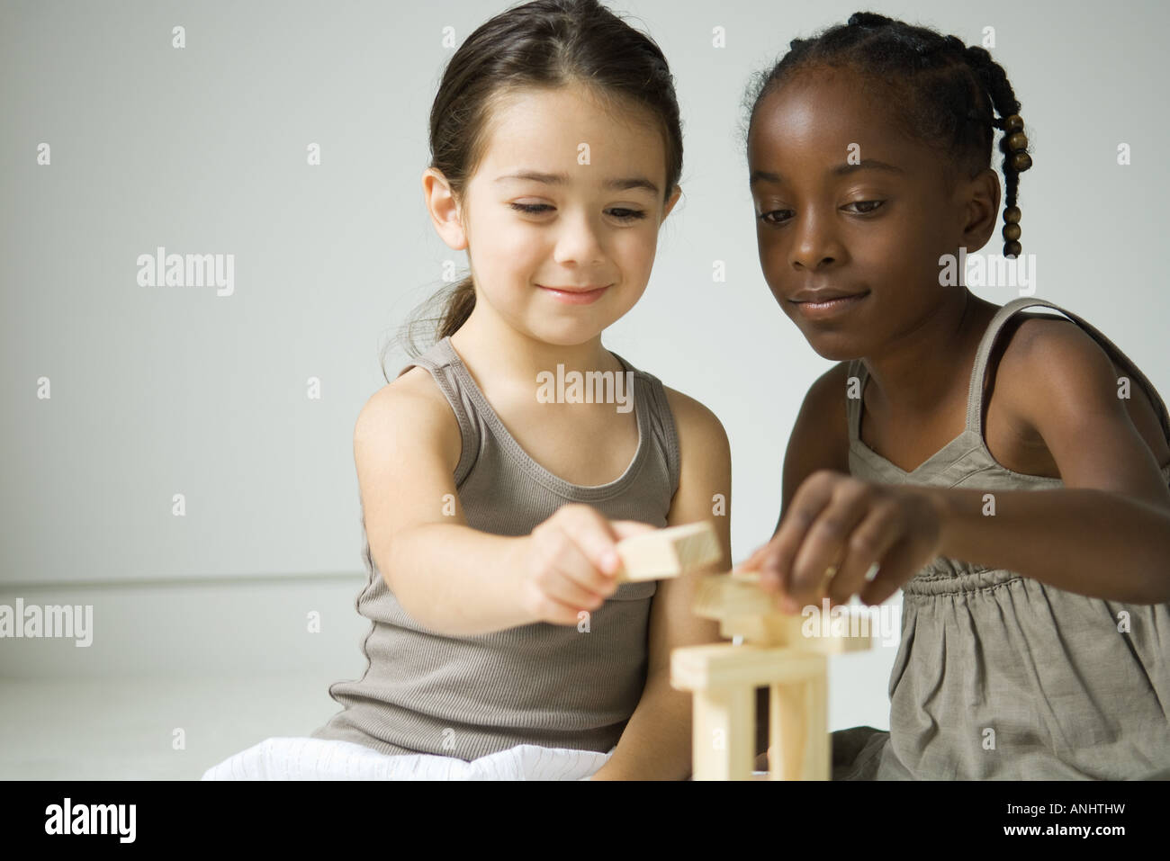 Two girls playing with blocks together, one smiling at camera Stock ...