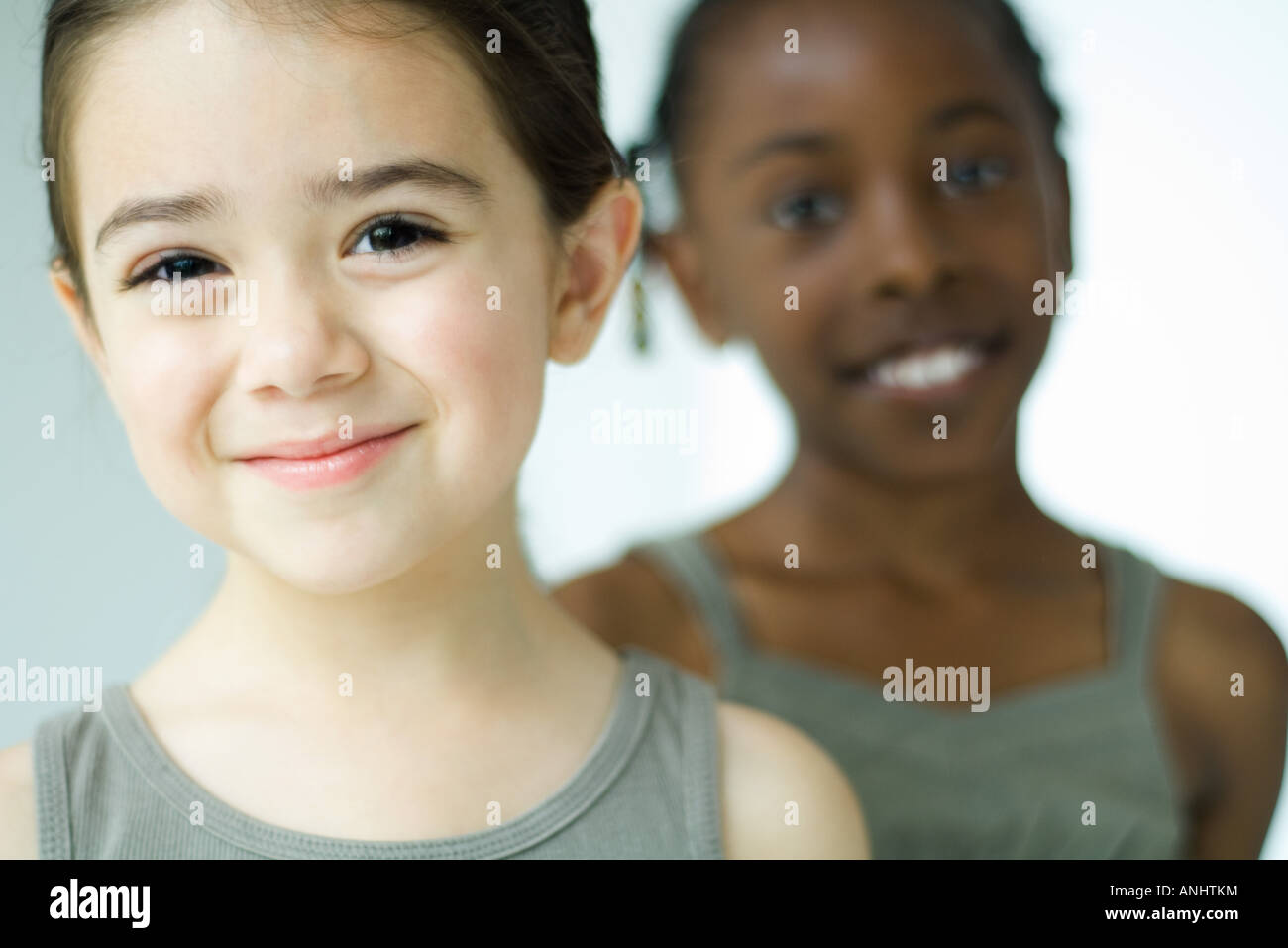 Girl smiling at camera, friend in background Stock Photo - Alamy