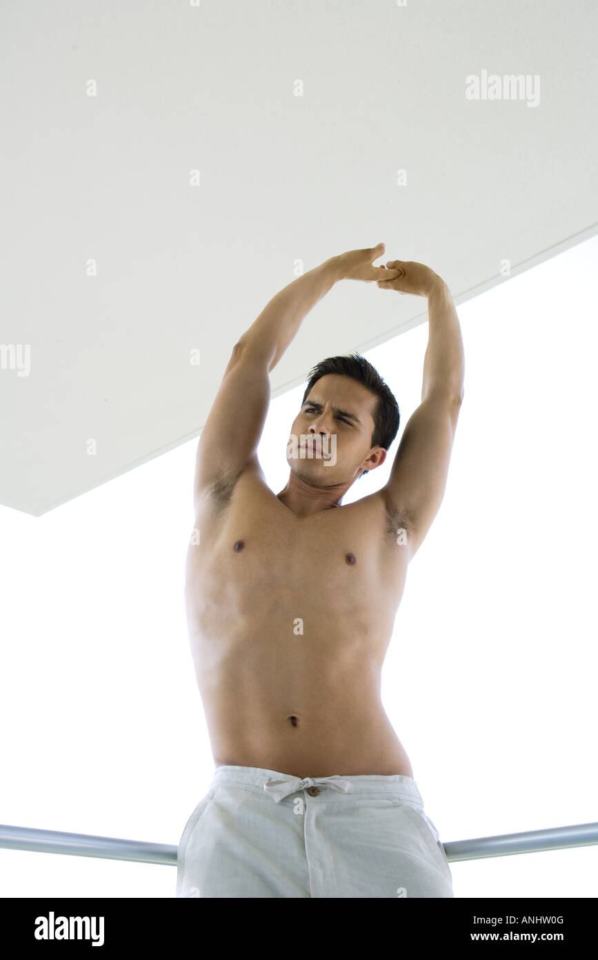 Barechested young man stretching arms over head, low angle view Stock ...