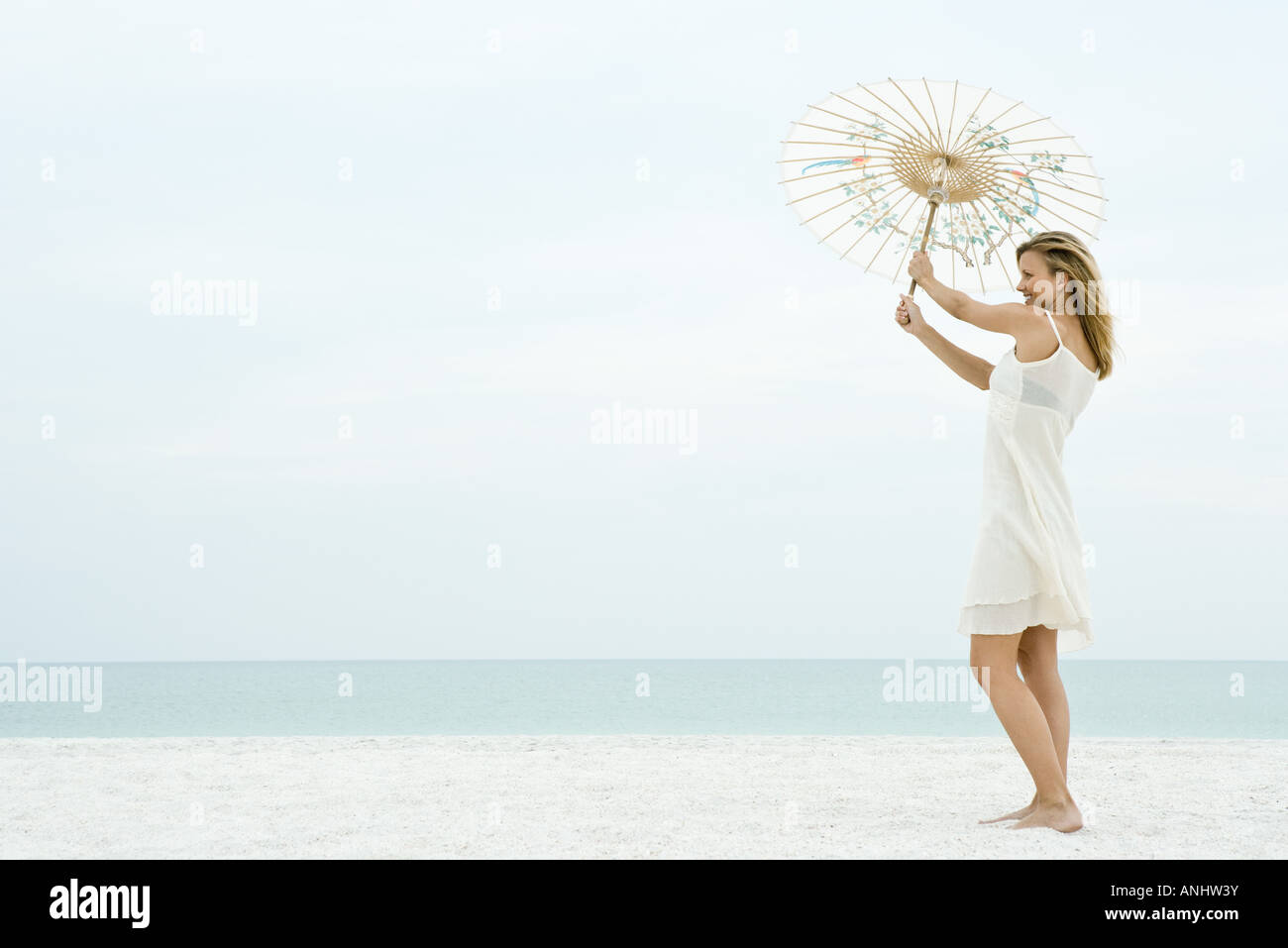 Woman holding parasol on beach, full length Stock Photo - Alamy