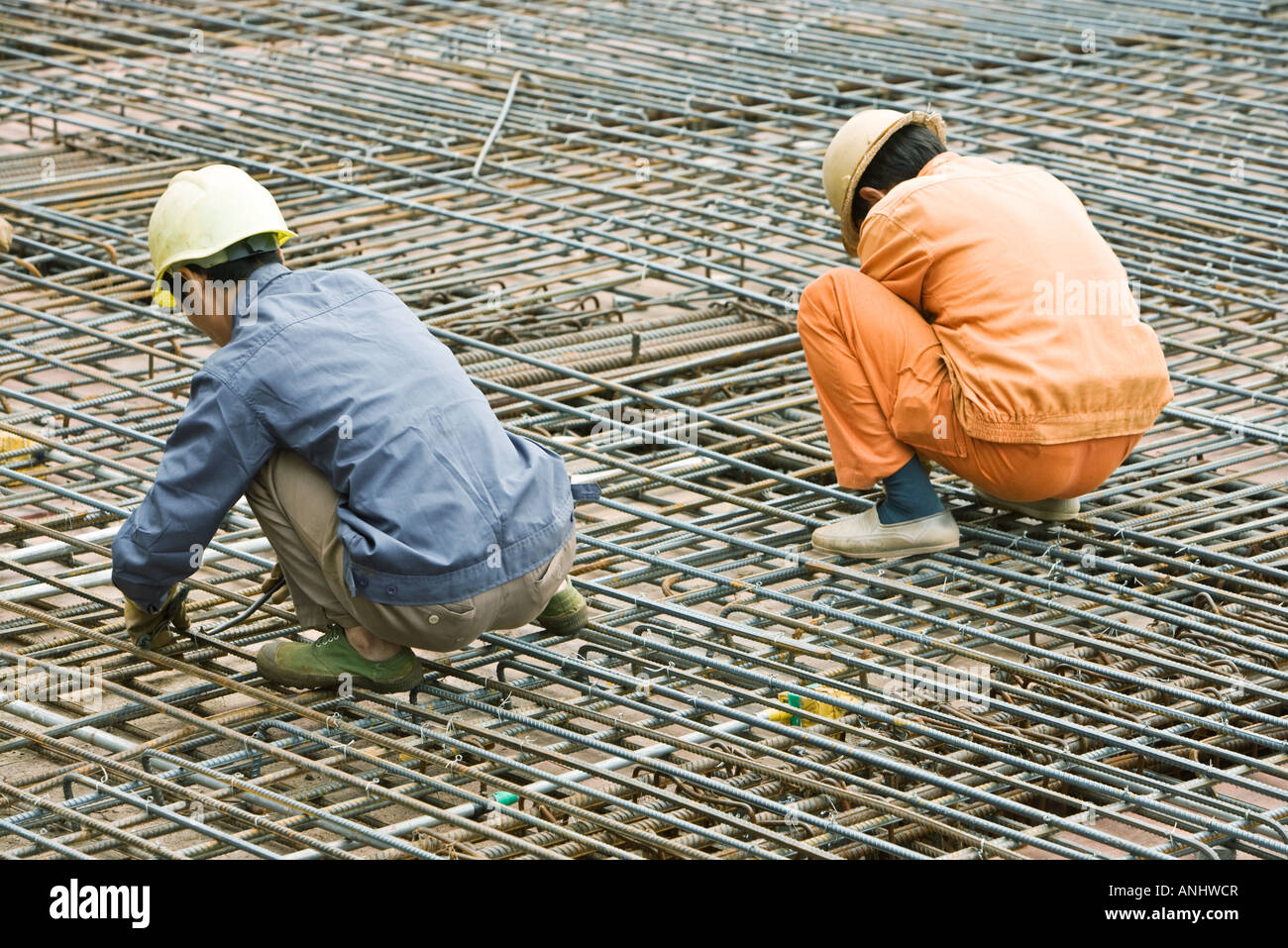 Rear view of two construction workers working at construction site hi ...
