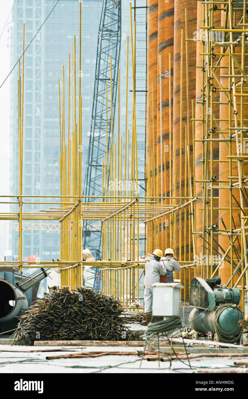 Rear view of two construction workers working at construction site hi ...