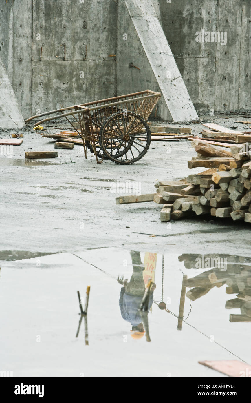 Construction worker at construction site, reflected in puddle of water ...