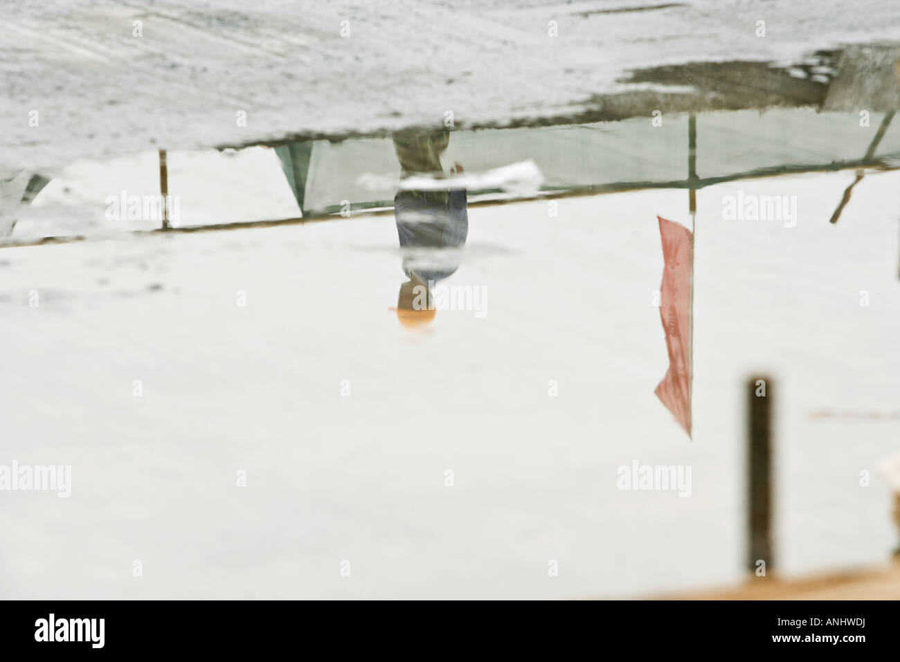 Construction worker at construction site, reflected in puddle of water ...