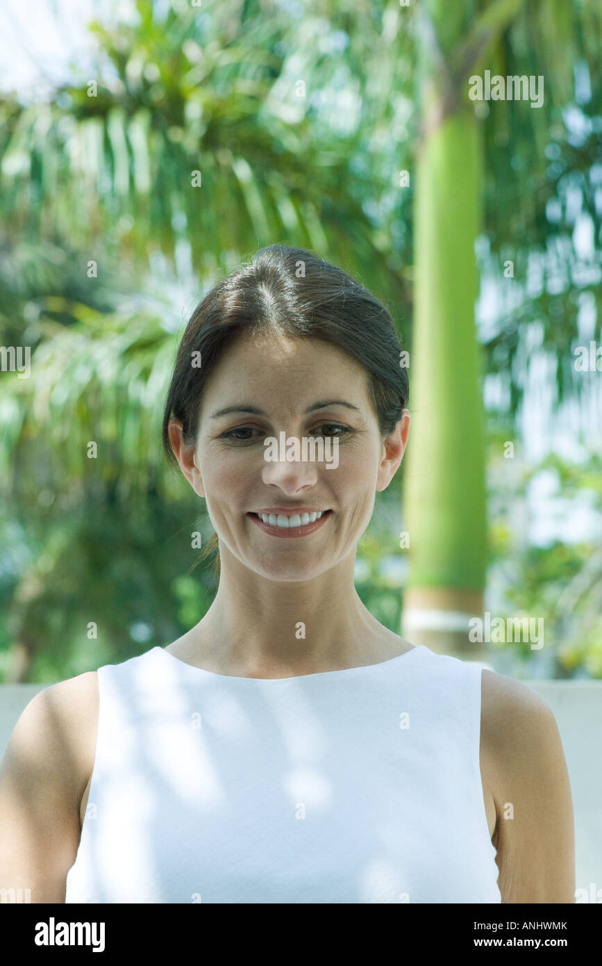 Woman smiling, palm trees in background, head and shoulders, portrait ...