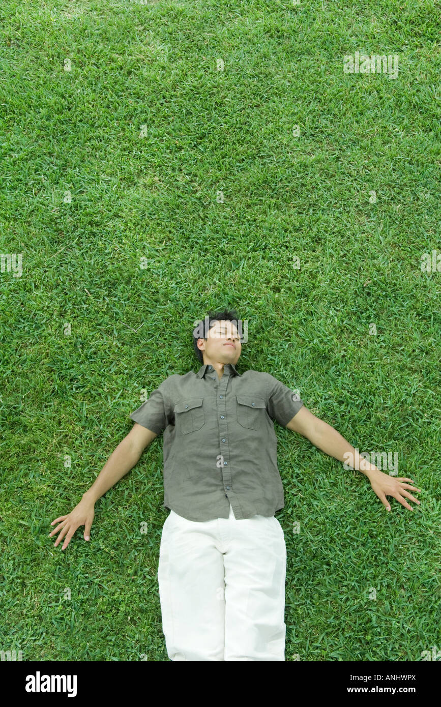 Man lying on back in grass, eyes closed Stock Photo - Alamy