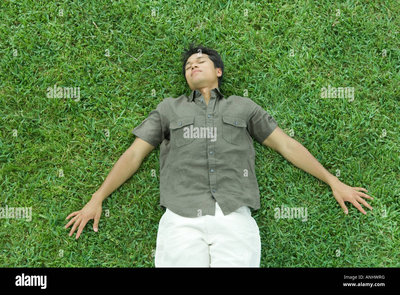 Man lying on back in grass, eyes closed Stock Photo - Alamy