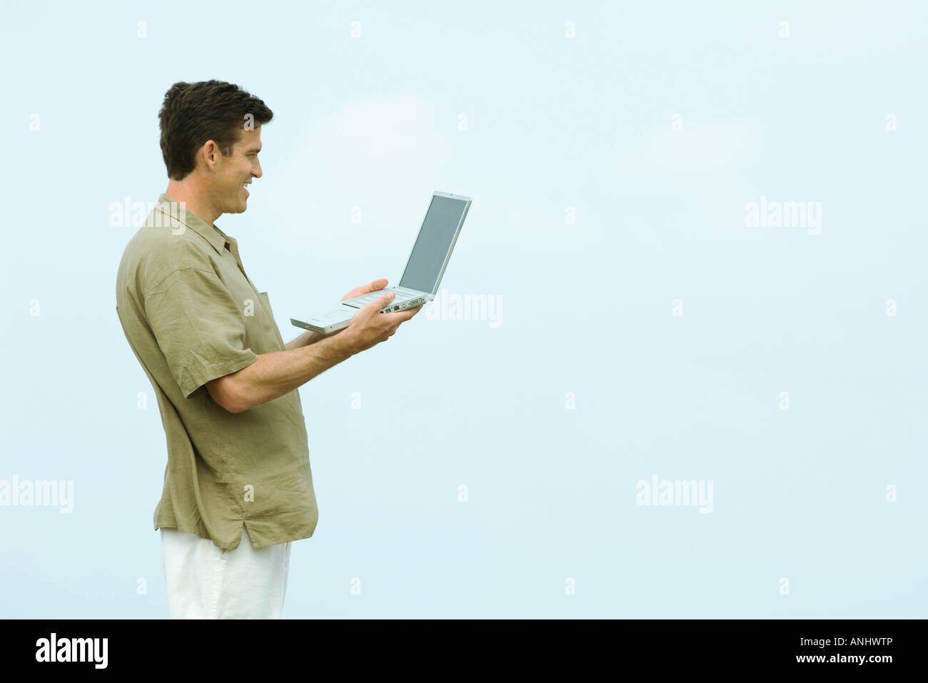 Man standing, using laptop, side view Stock Photo - Alamy