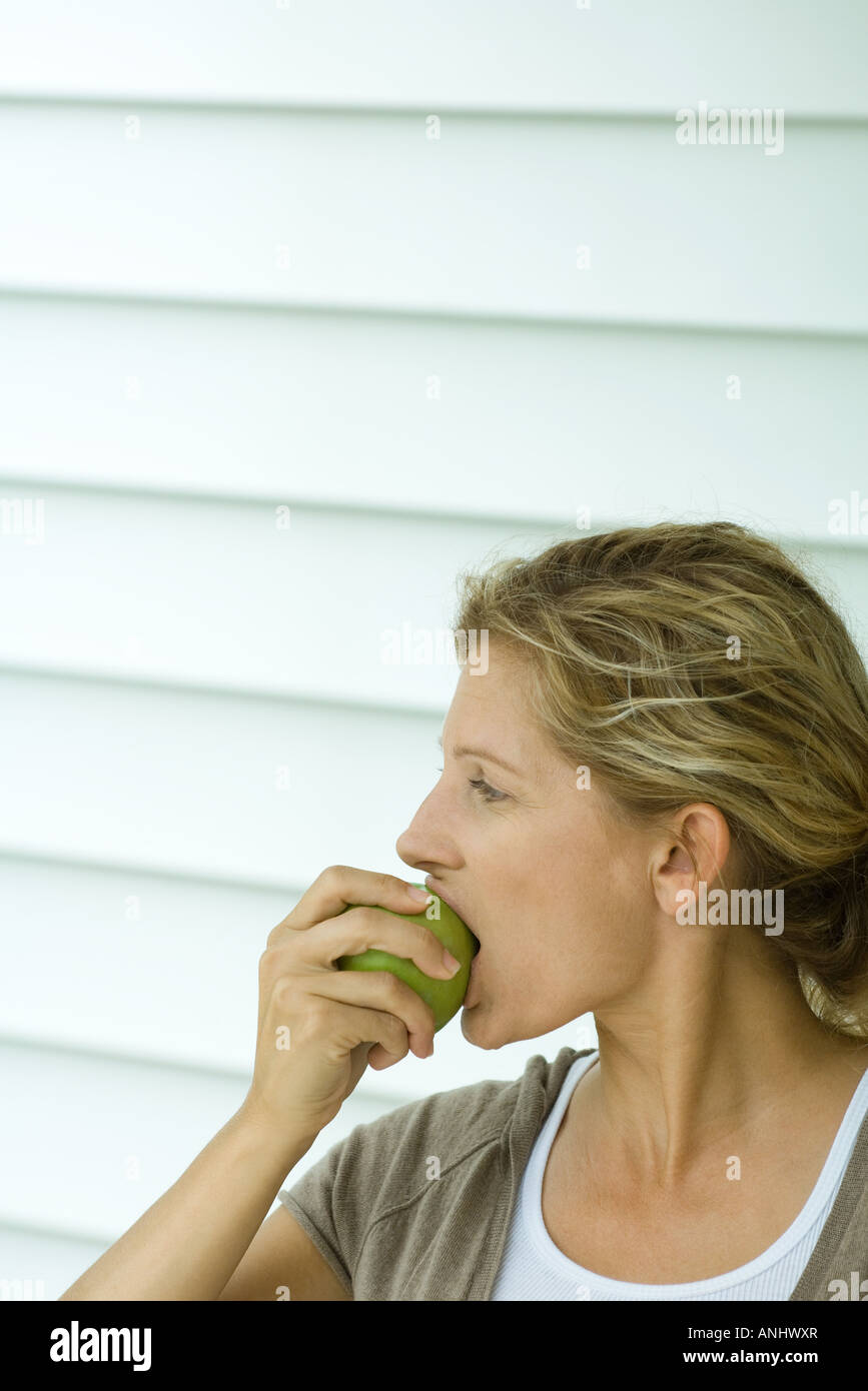 Woman taking bite out of apple, side view Stock Photo - Alamy