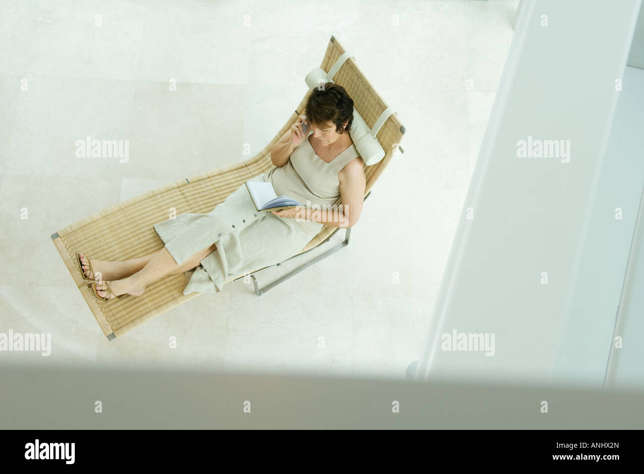 Woman sitting on lounge chair writing in diary, high angle view Stock ...