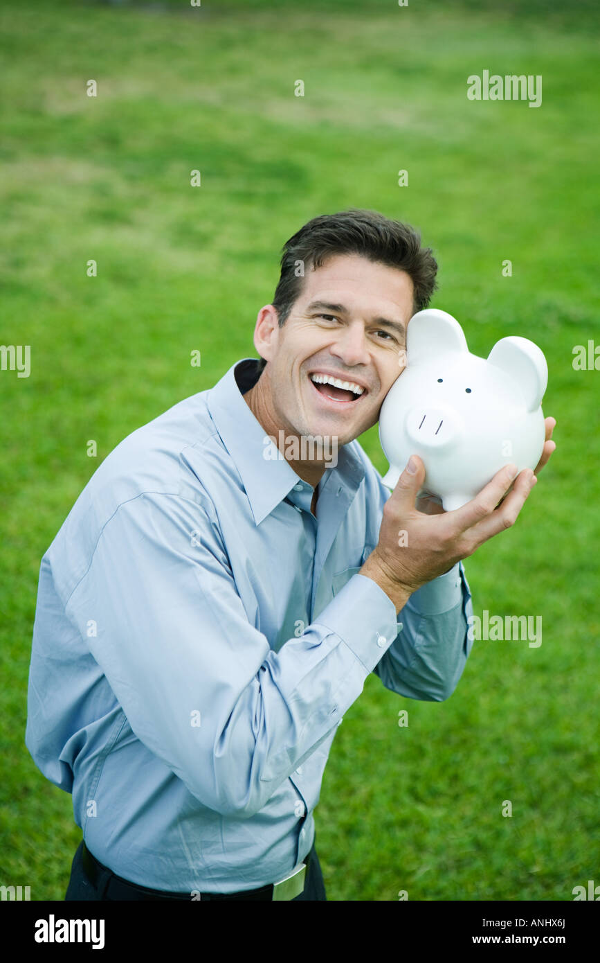 Man holding piggy bank, cheek to cheek, smiling Stock Photo - Alamy