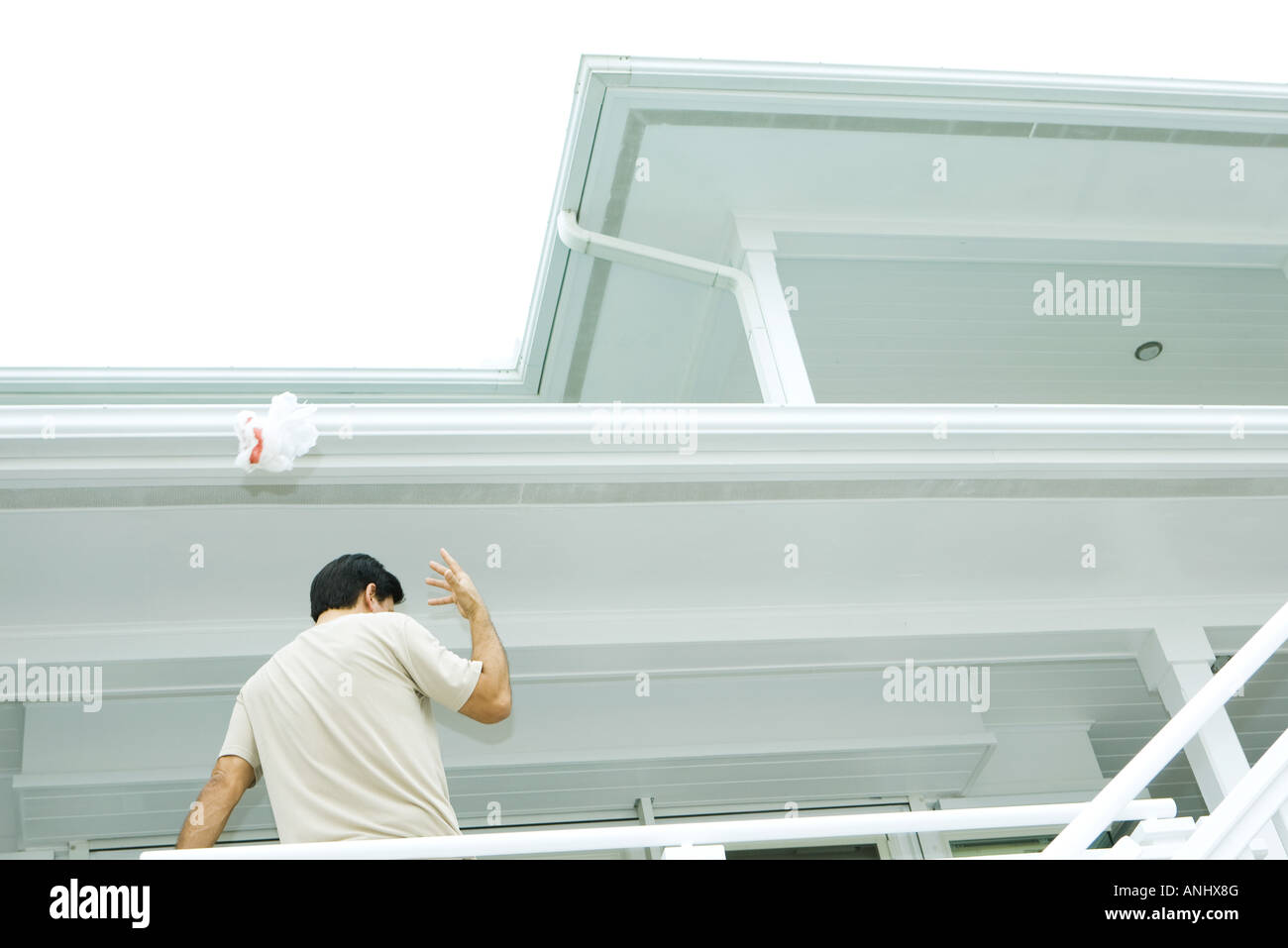 Man standing on deck, throwing litter over shoulder, low angle view ...