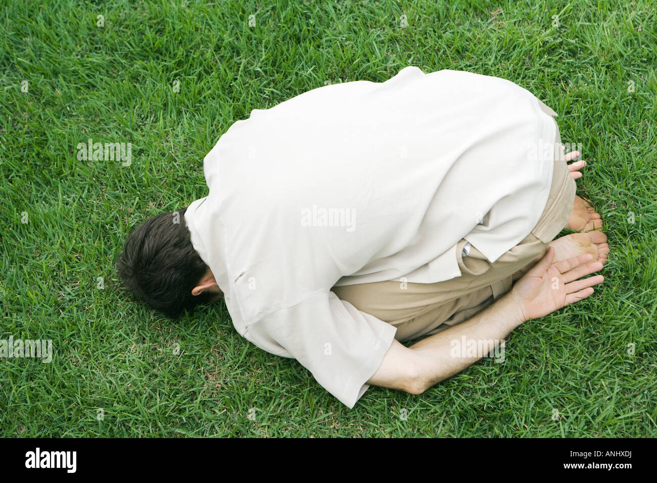 Man doing child's pose on grass, high angle view Stock Photo - Alamy