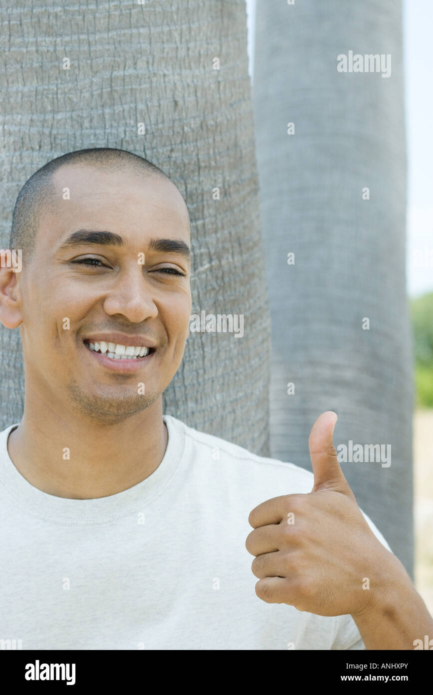 Man making thumbs up gesture and smiling at camera Stock Photo - Alamy