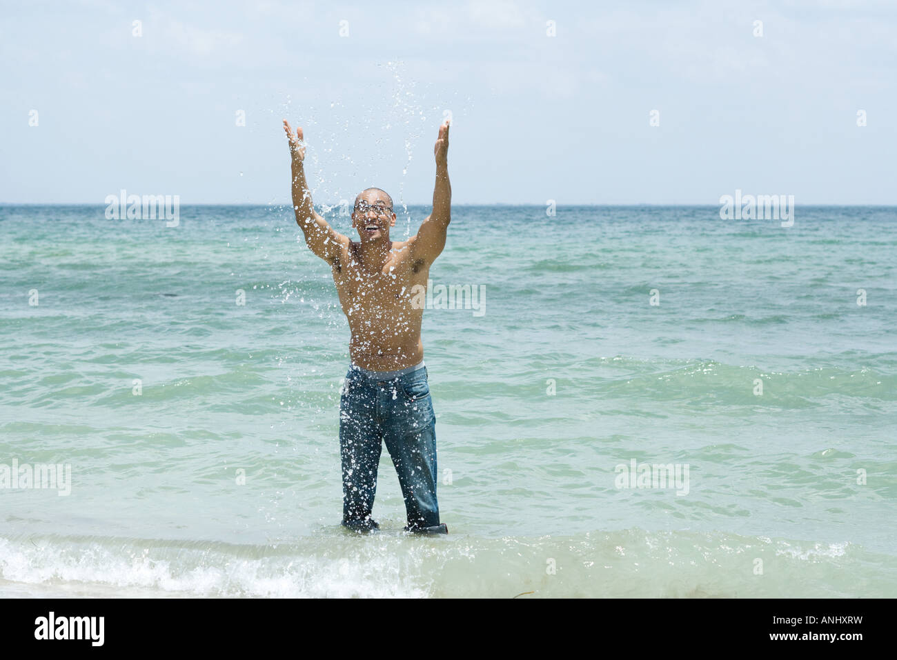 Man splashing in ocean, arms raised Stock Photo - Alamy