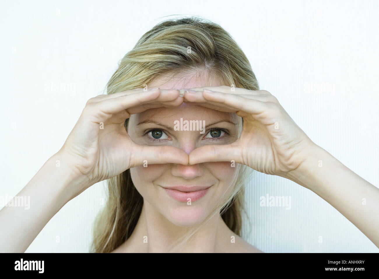 Woman looking through finger frame at camera, smiling Stock Photo - Alamy
