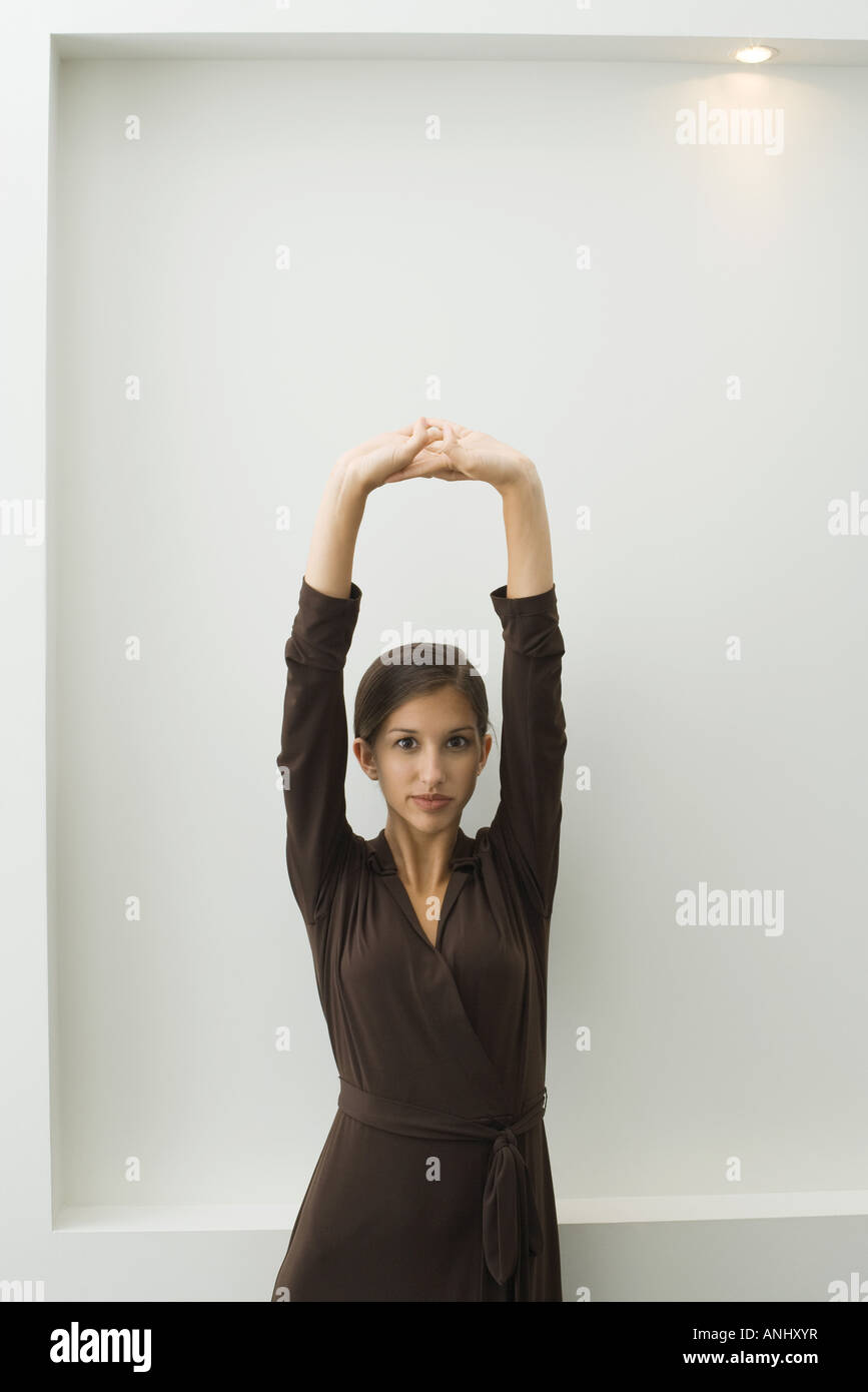 Teenage girl standing with arms raised, clasped hands, looking at ...