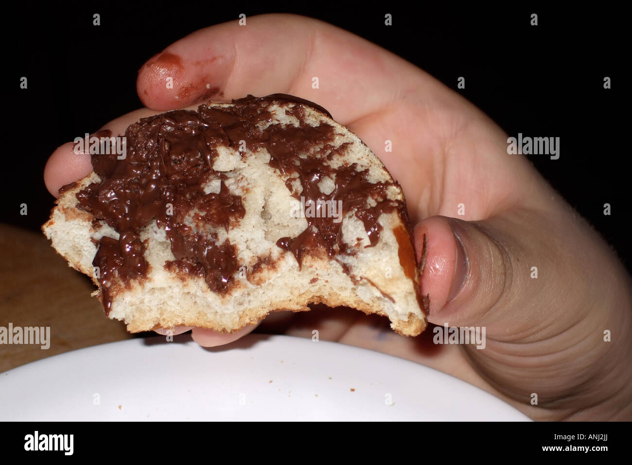 Hand of a child holding a bread roll with hazelnut spread Stock Photo ...