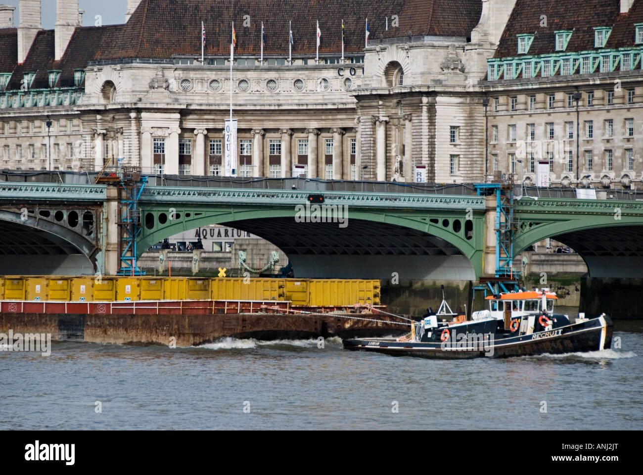 A tug towing cargo barges passes under Westminster Bridge, London, UK ...