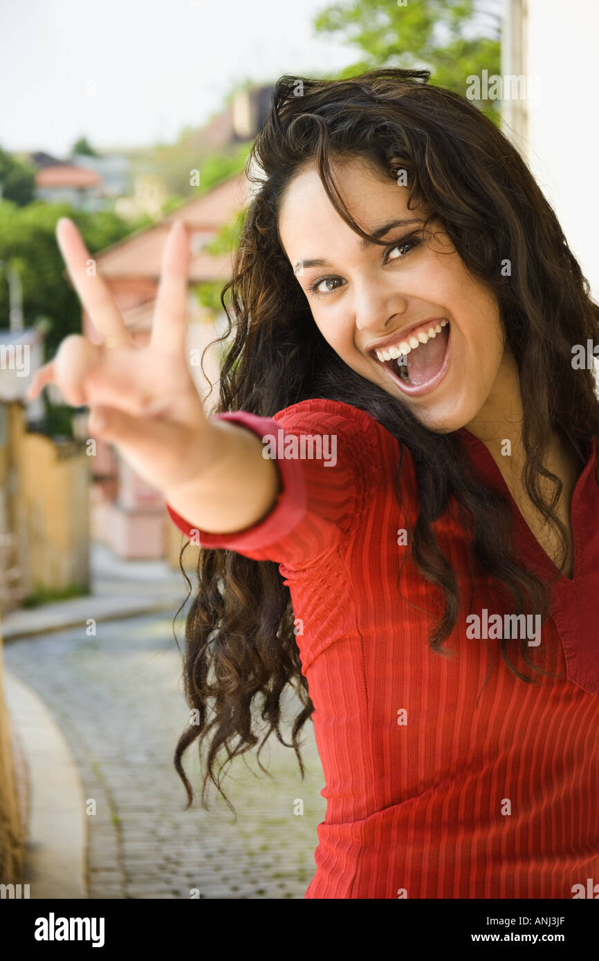 Portrait of a young woman giving a peace sign Stock Photo - Alamy