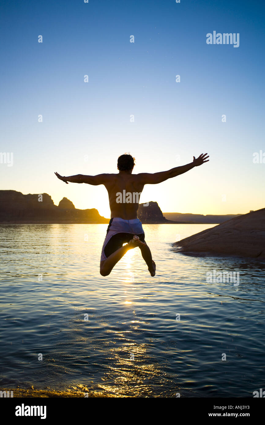 Rear view of a young man jumping into a lake Stock Photo - Alamy