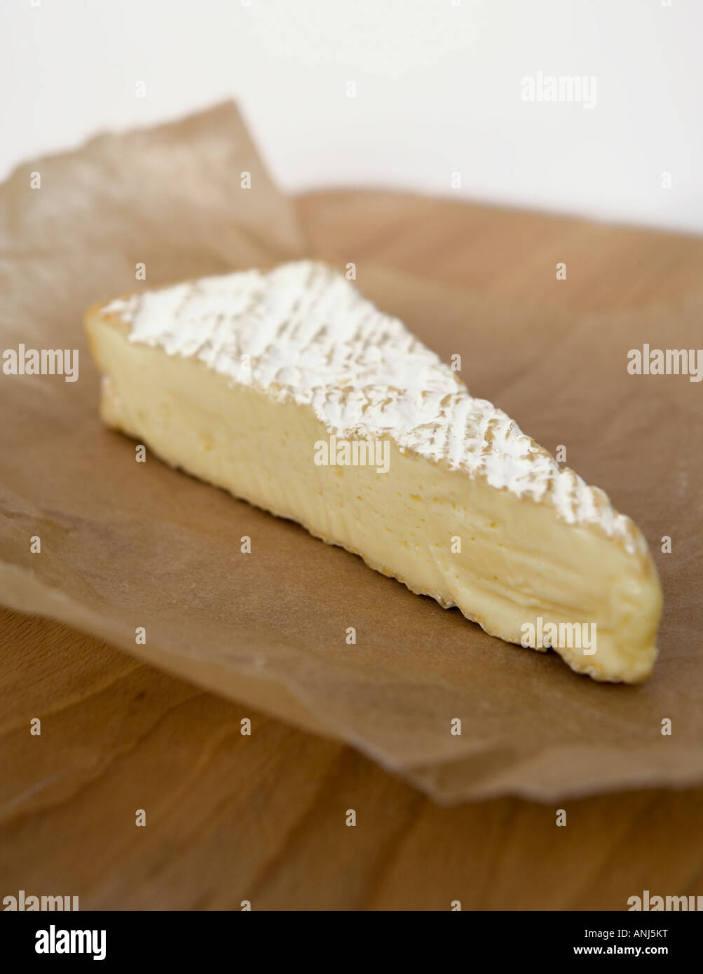 Slice of Brie cheese on brown parchment paper Stock Photo - Alamy