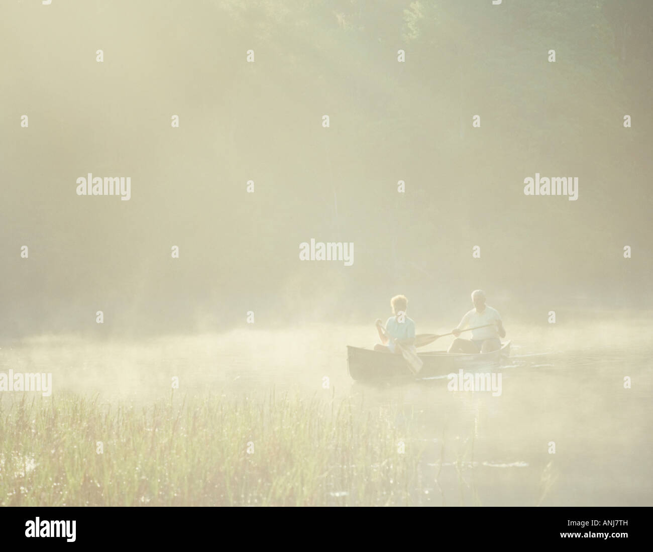 Senior man and woman couple canoeing in mist morning light on Rainbow ...
