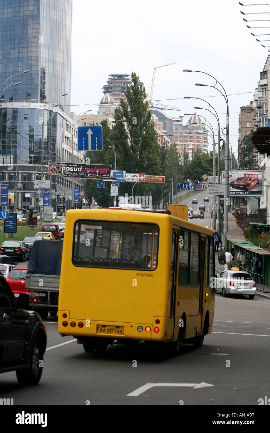 Yellow city bus on a busy street in Kyiv with cars, modern buildings ...