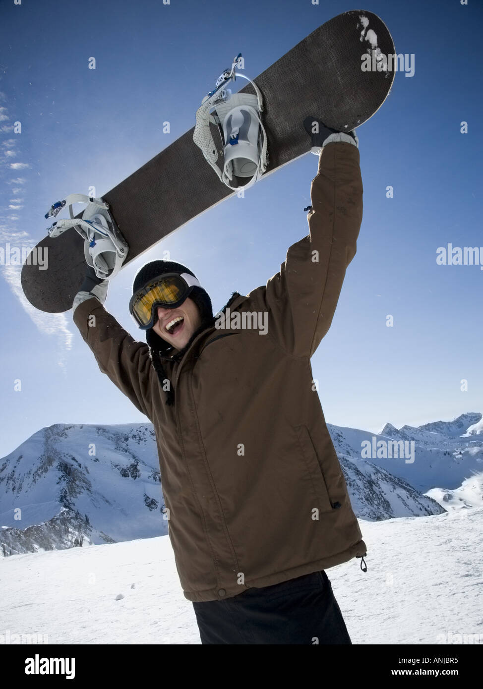 Low angle view of a young man lifting a snowboard and shouting Stock ...