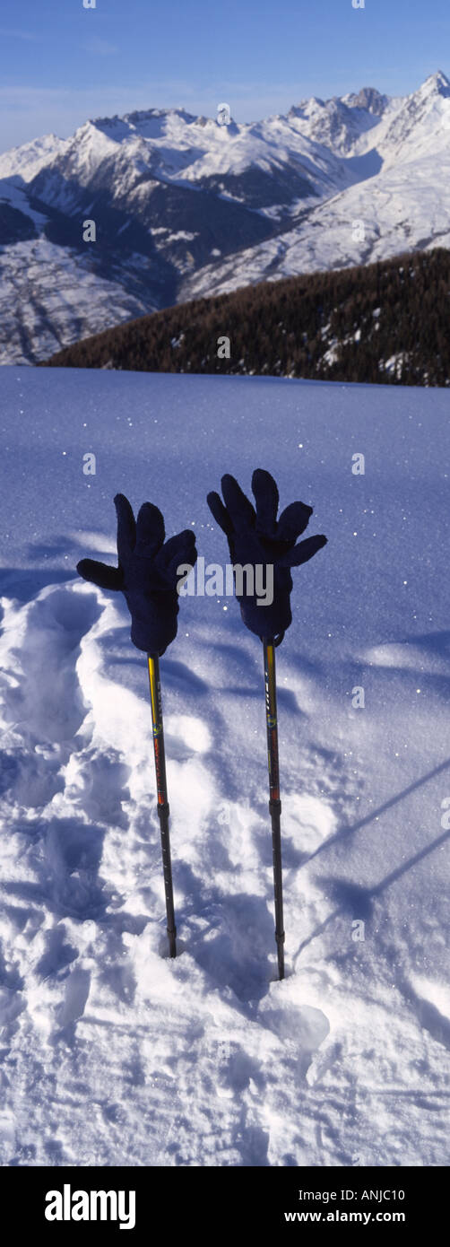 Ski poles stuck in deep snow with gloves on top Stock Photo - Alamy