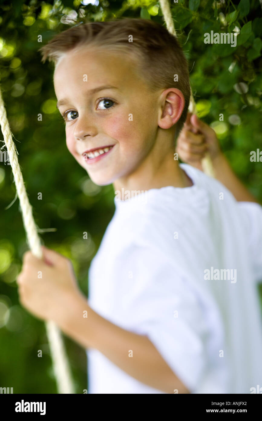 Portrait of a boy swinging on a swing Stock Photo - Alamy
