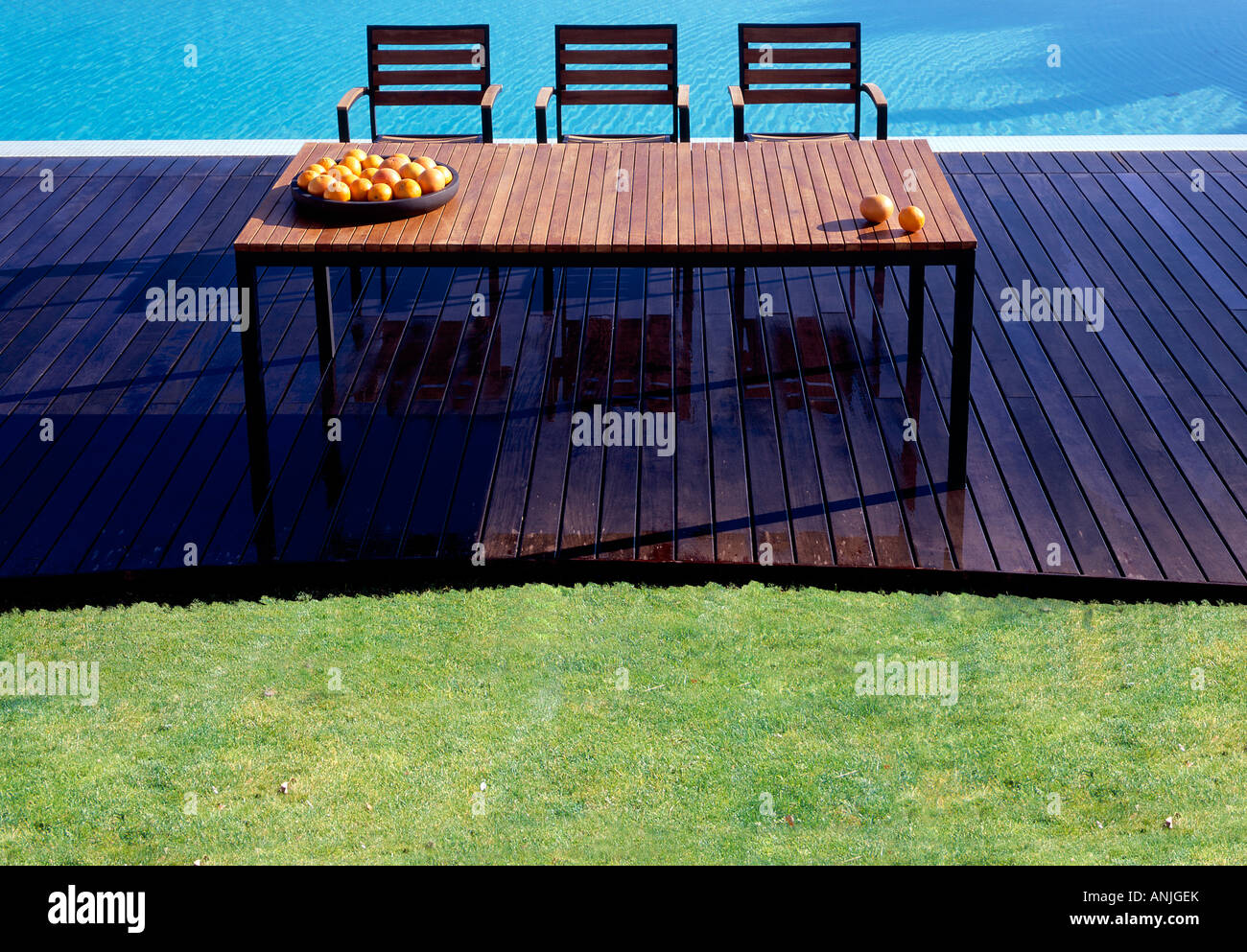 View of a table and chairs alongside a swimming pool Stock Photo - Alamy