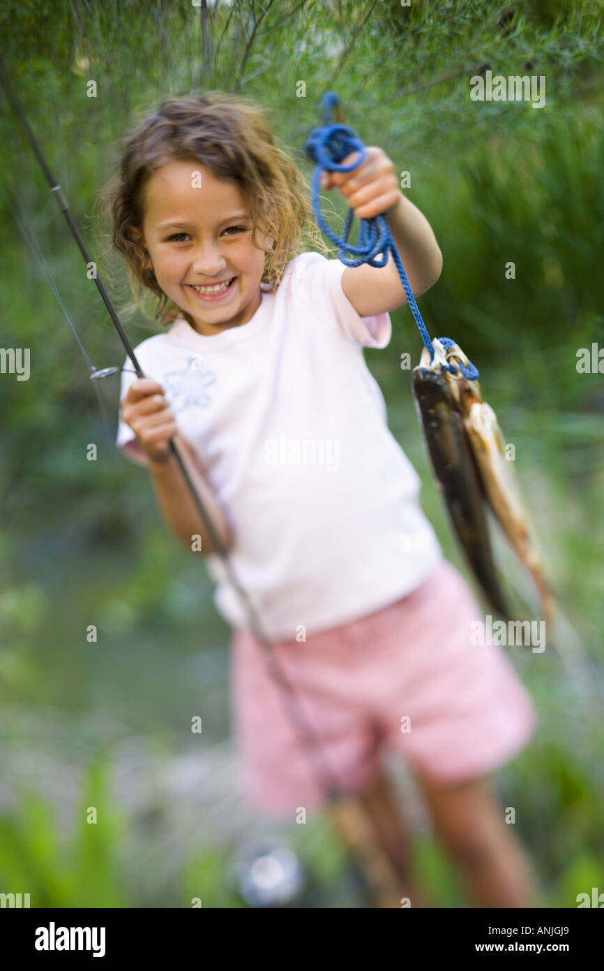 Portrait of a girl holding fishing rod and a fish Stock Photo - Alamy