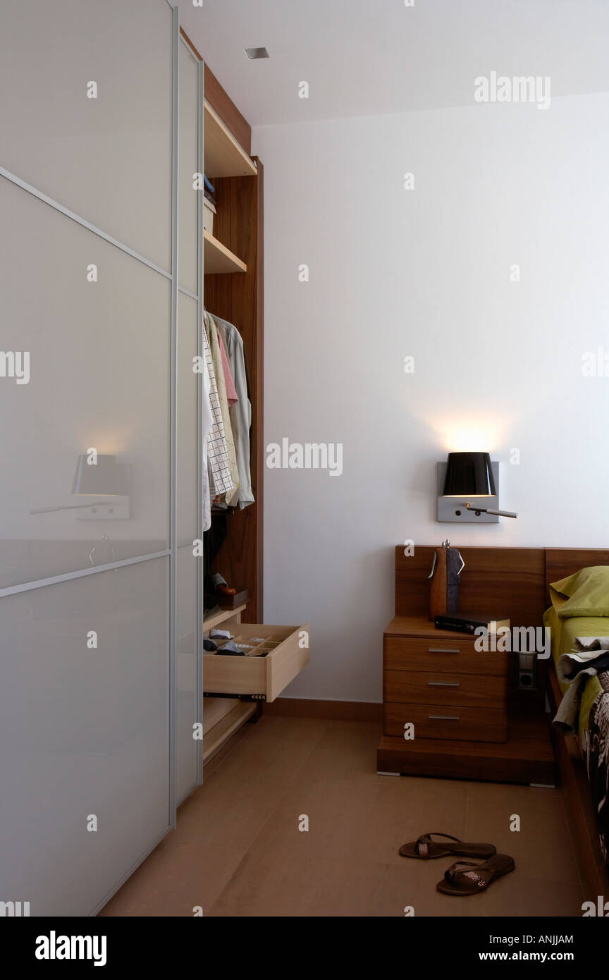 View of bedroom with open cupboard and drawers and bed side table Stock ...