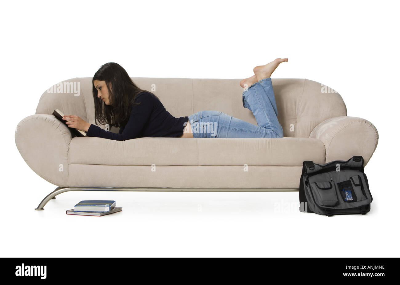 Side profile of a young woman lying on a couch and reading a book Stock ...