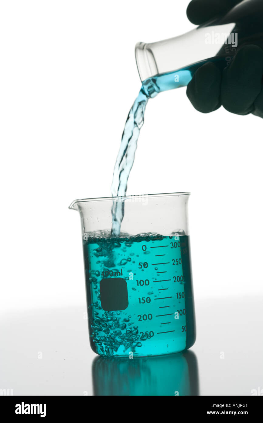 Person pouring chemical into a beaker Stock Photo - Alamy