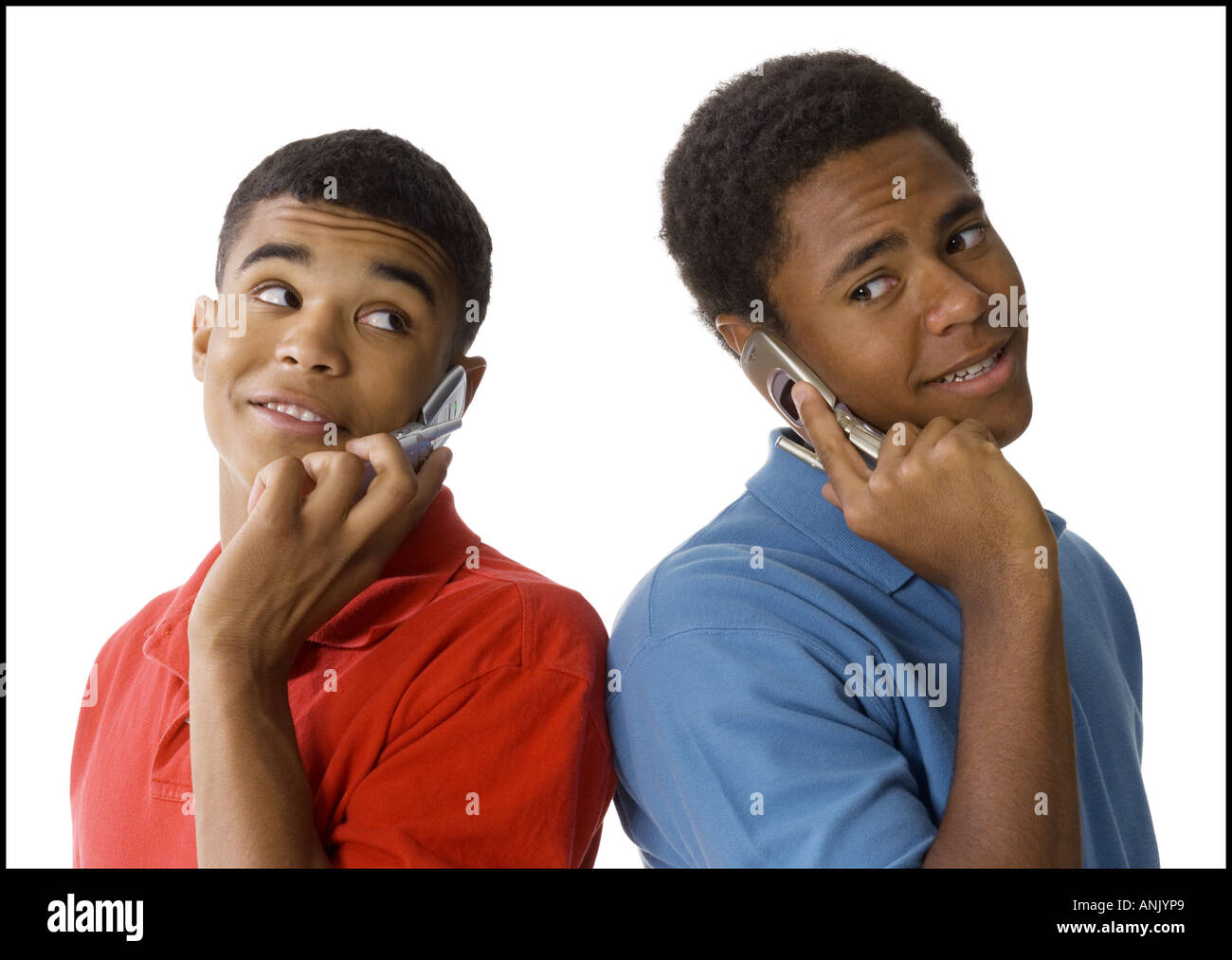 Close up of two young men standing back to back talking on mobile ...