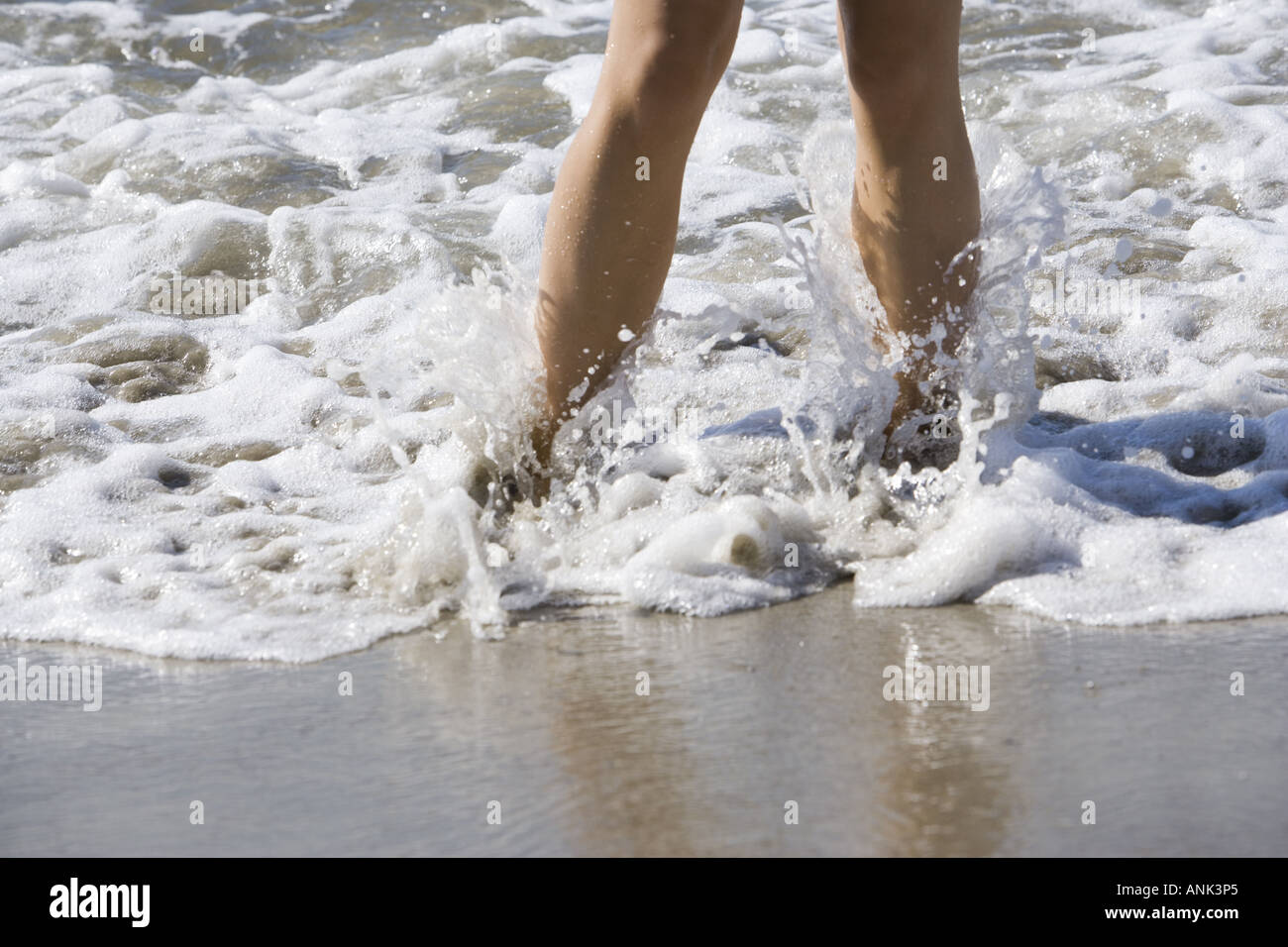 Legs from the knee down in shallow water at the beach Stock Photo - Alamy