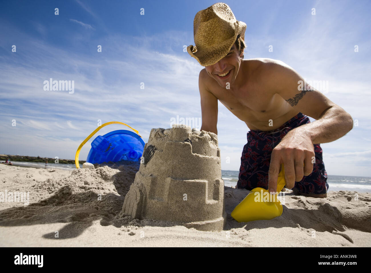 Low angle view of a young man digging sand on the beach Stock Photo - Alamy