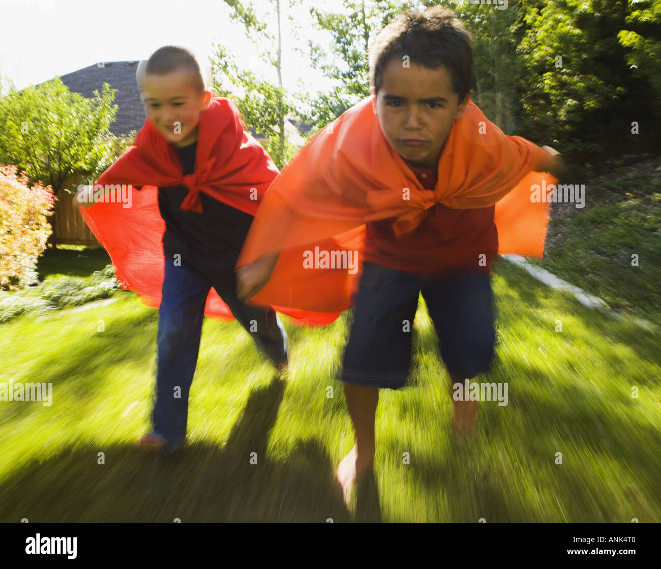 Low angle view of two boys wearing capes and running Stock Photo - Alamy