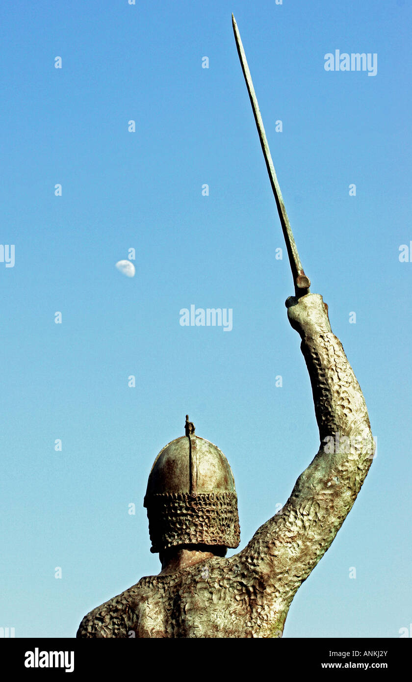 Back view of statue of warrior holding upraised sword at moonset in ...