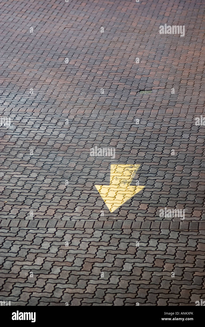 A yellow arrow on a brick driveway Stock Photo - Alamy